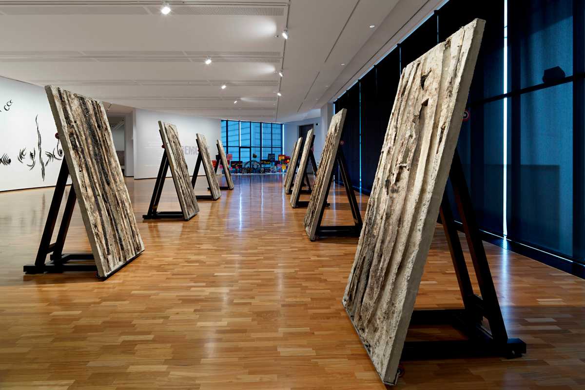 Two rows of large concrete panels with burned sections of tree branch ...