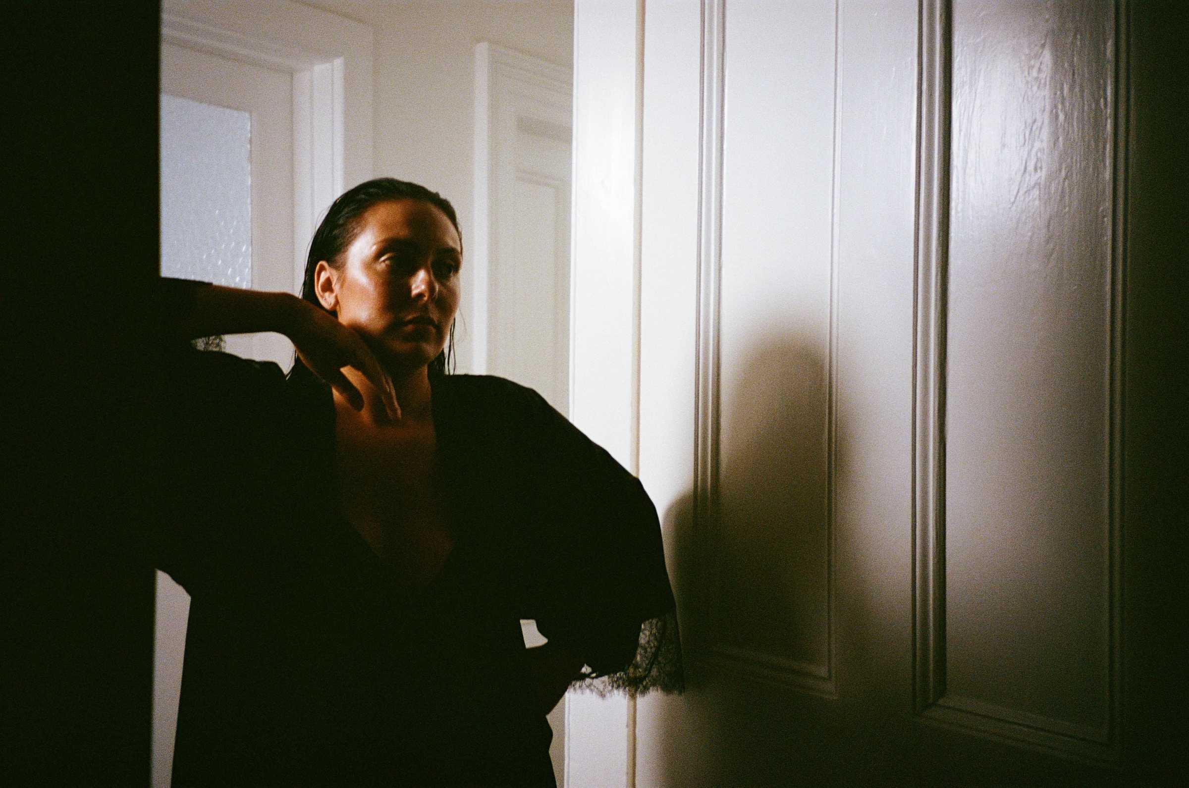 A waist up photograph of a woman draped in a black silk and lace shawl ...